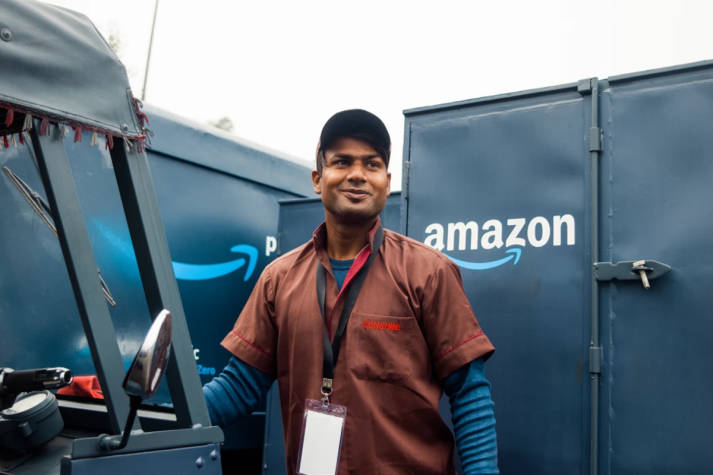 South Asian DSP owner standing between several Amazon delivery vans ...