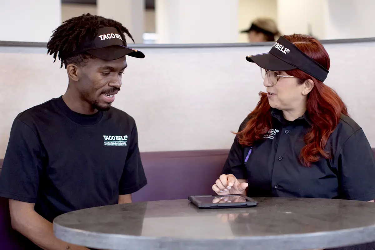 Black male and Hispanic female Taco Bell Team Members sitting at a ...