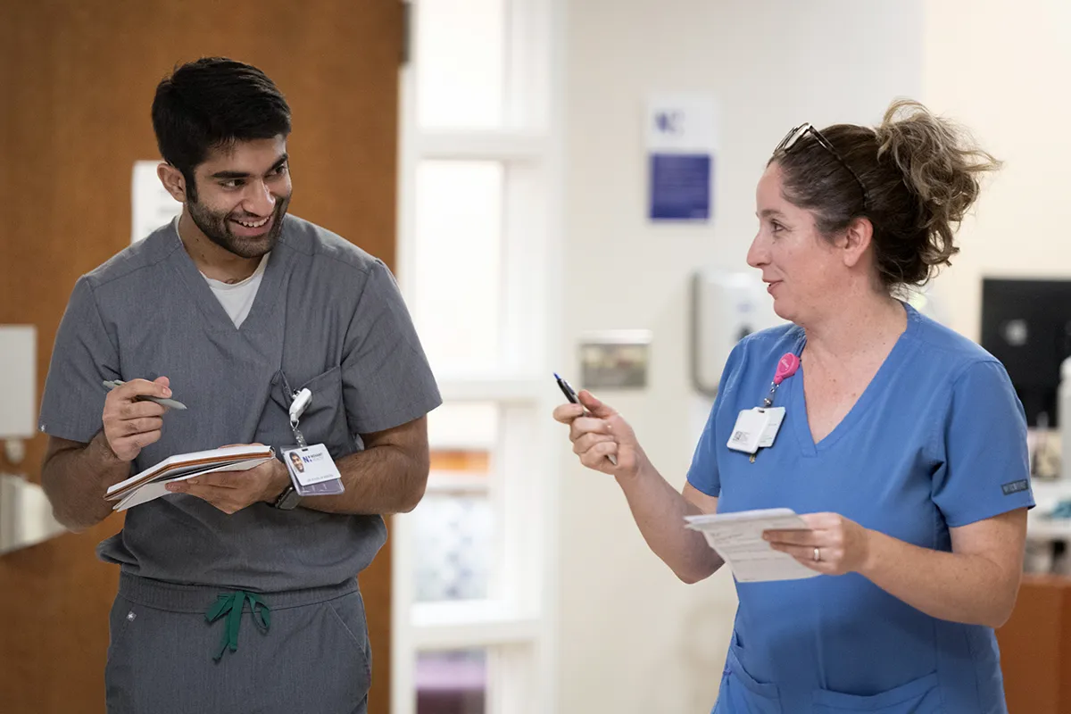 Male and female nurses, holding notebooks and pens, smiling and ...